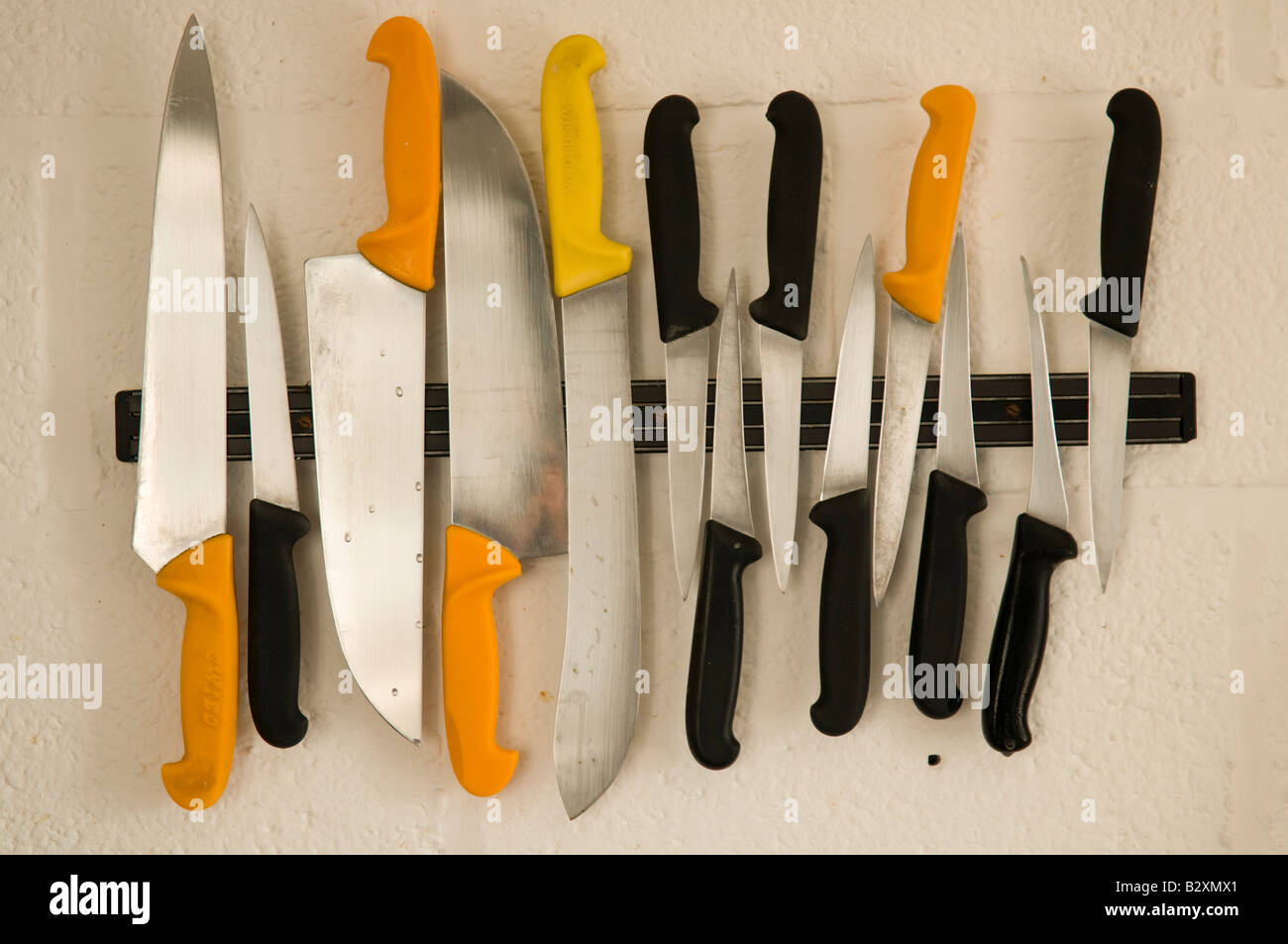 row of professional chef knives on magnetic holder in restaurant ...