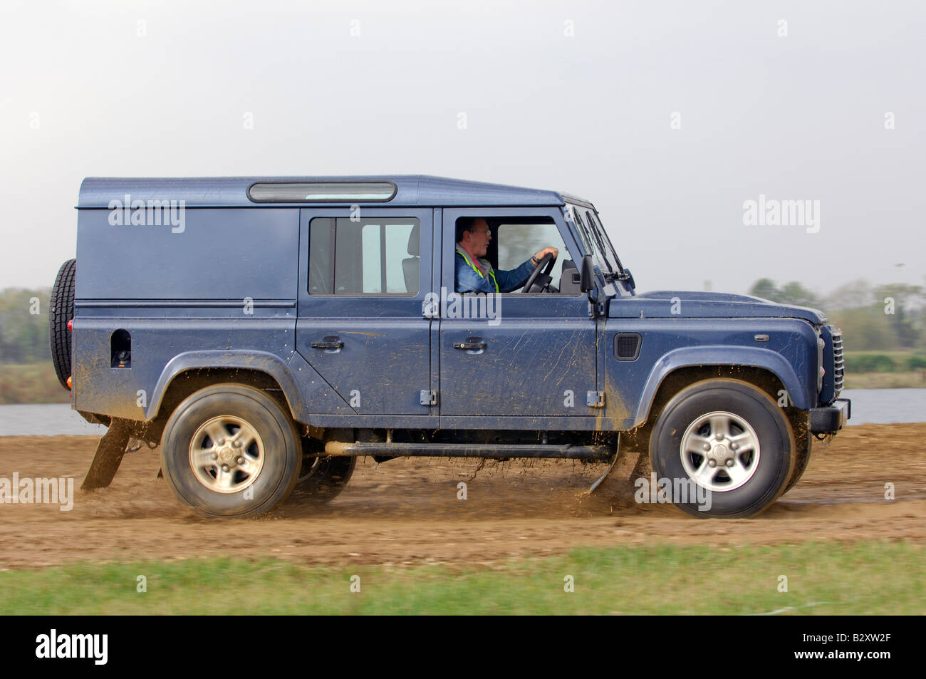 land rover defender 4x4 vehicle off roading down a muddy lane in the ...