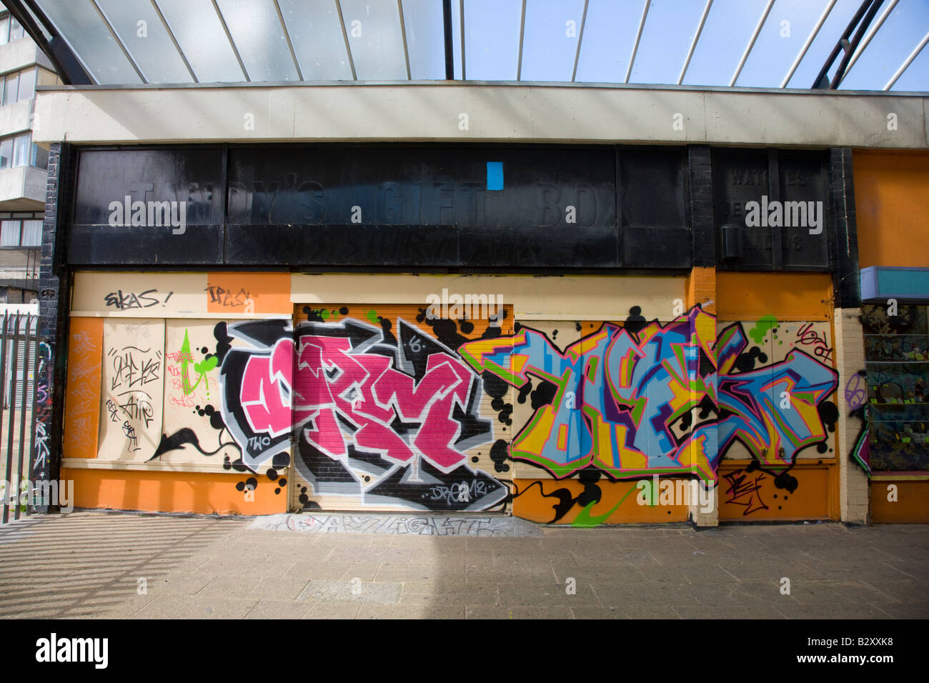 Graffiti on arcade of shops underneath a tower block of flats in ...