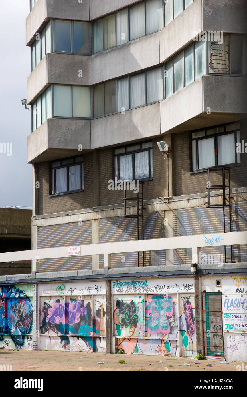 Graffiti on arcade of shops underneath a tower block of flats in ...