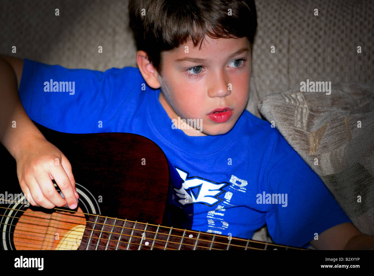 Young boy playing a guitar in a spotlight Stock Photo - Alamy