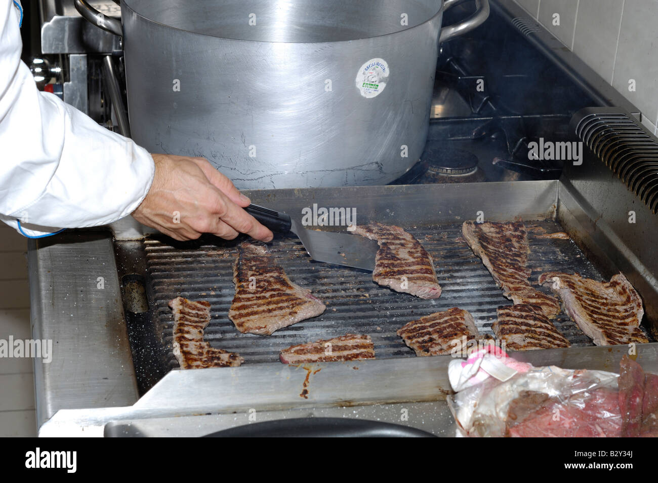 Chef cooking beefs in a professional grill of a restaurant's kitchen ...