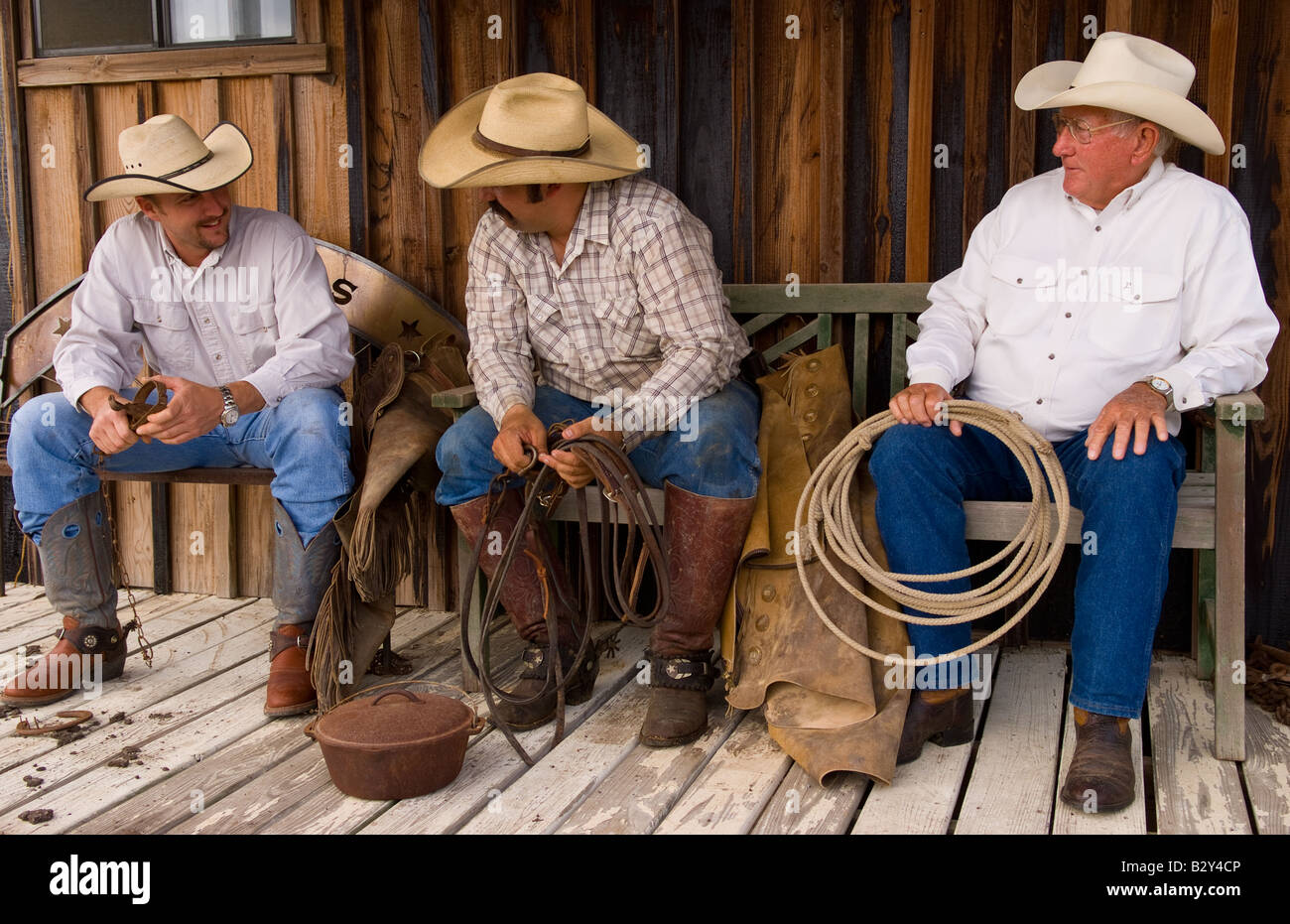 The cowboy life in the USA West as cowboys relax and talk on old porch ...