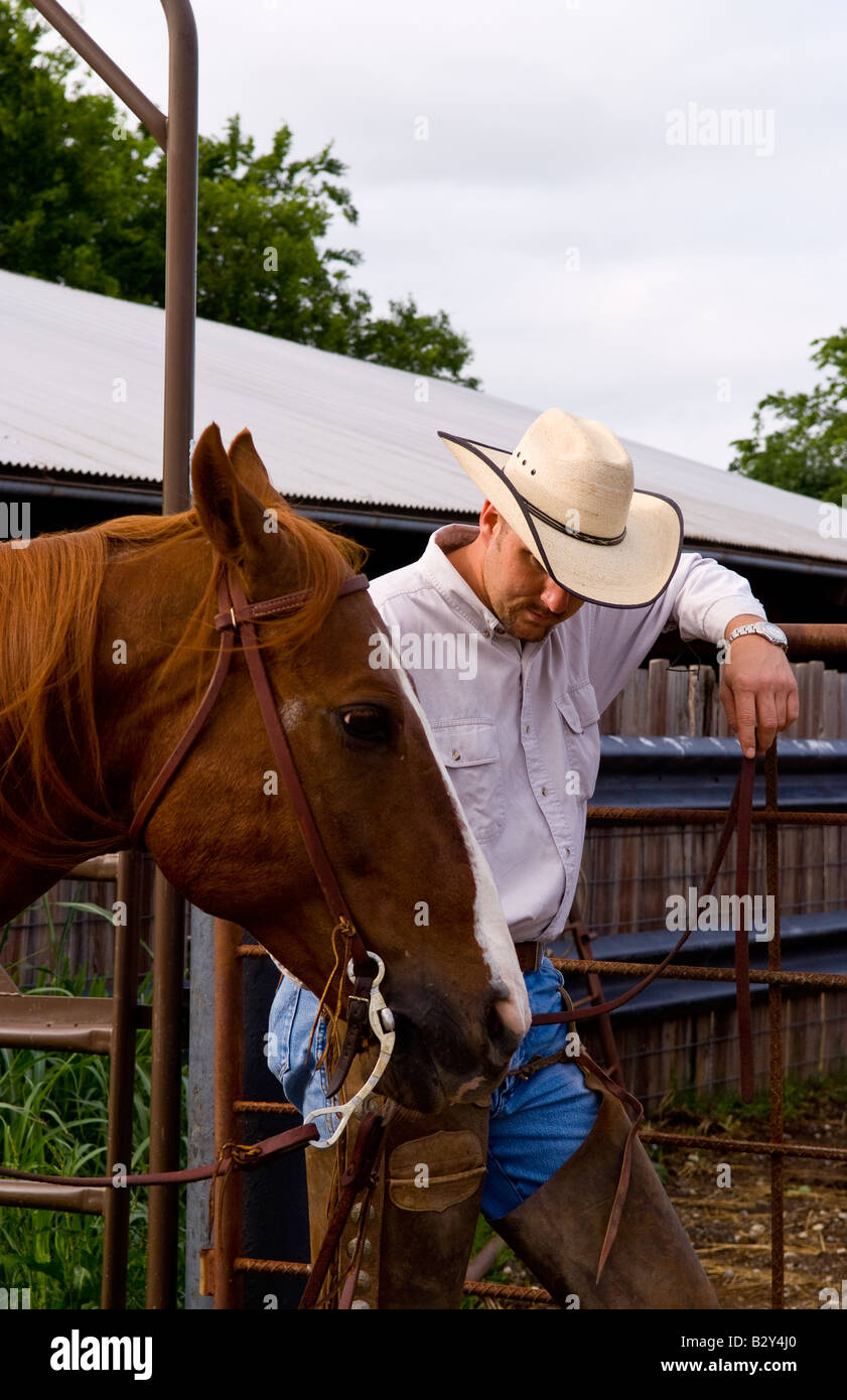 The cowboy life in the USA West as cowboy relaxes by horse at ranch ...