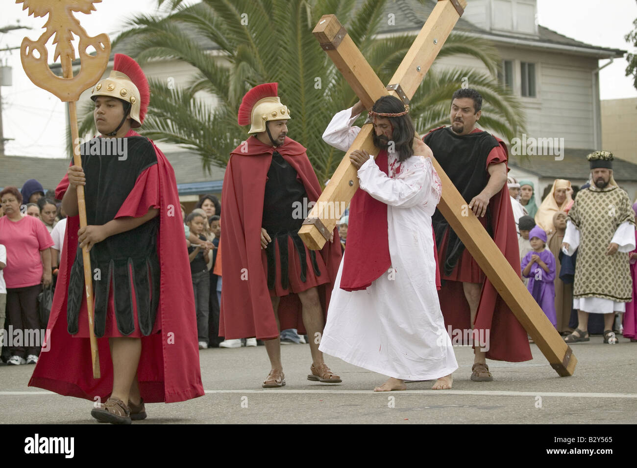An actor portraying Jesus Christ carrying a cross past crowds, Easter ...