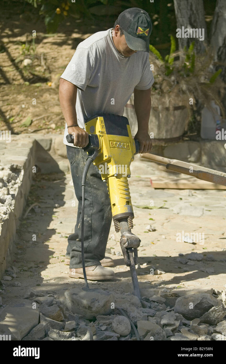 Hispanic male breaking concrete with yellow jackhammer Stock Photo - Alamy