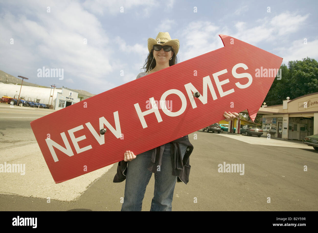 Girl holding red sign with arrow pointing up, that reads "New Homes For ...