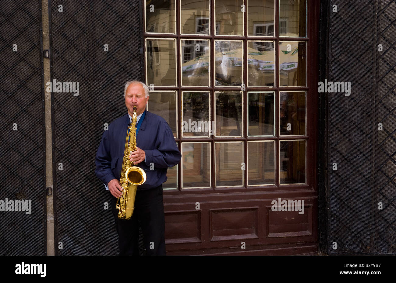 Old man playing music with saxaphone in dowtown city center in Lviv ...