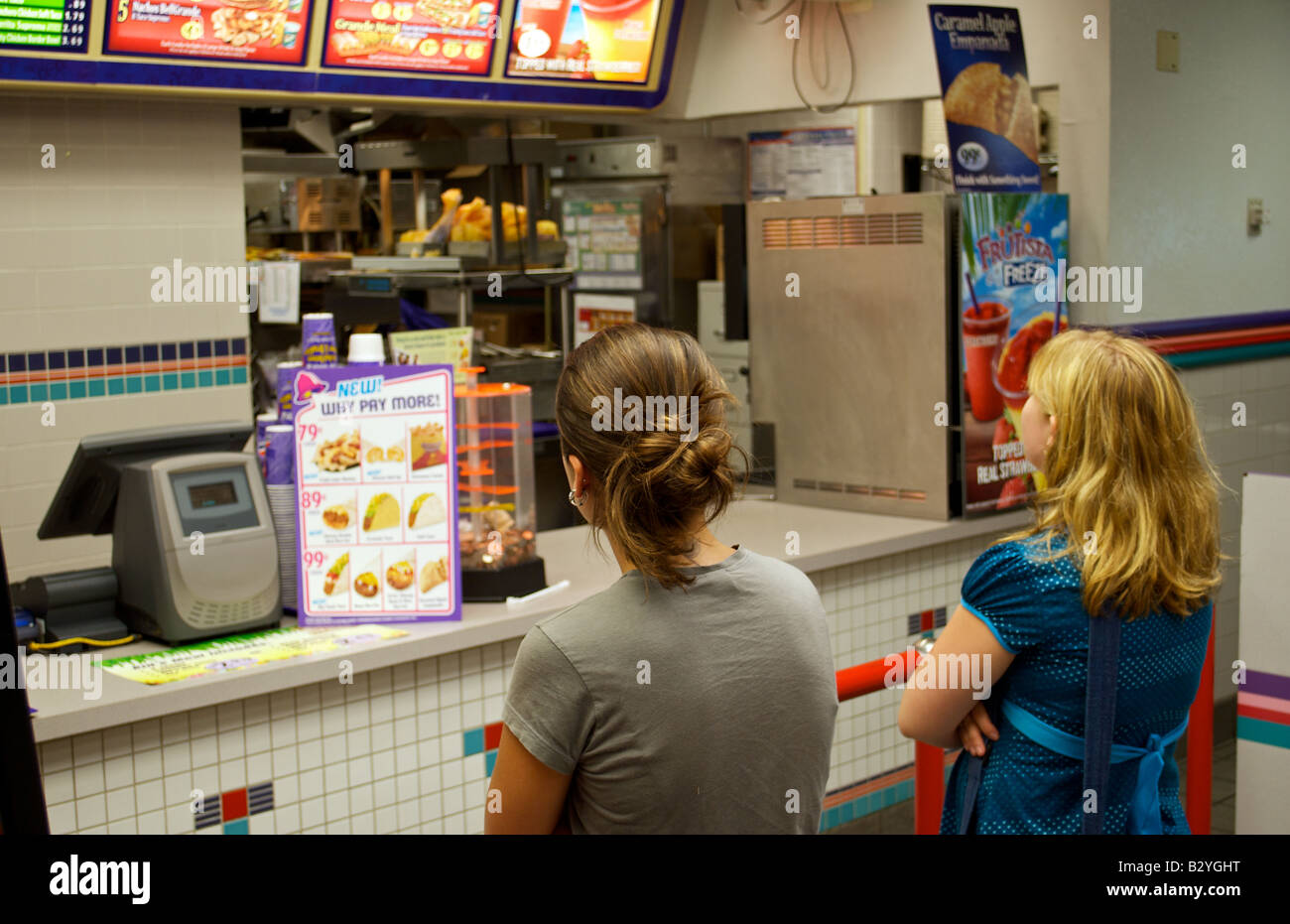 two young girls standing in line at the fast food restaurant ready to ...