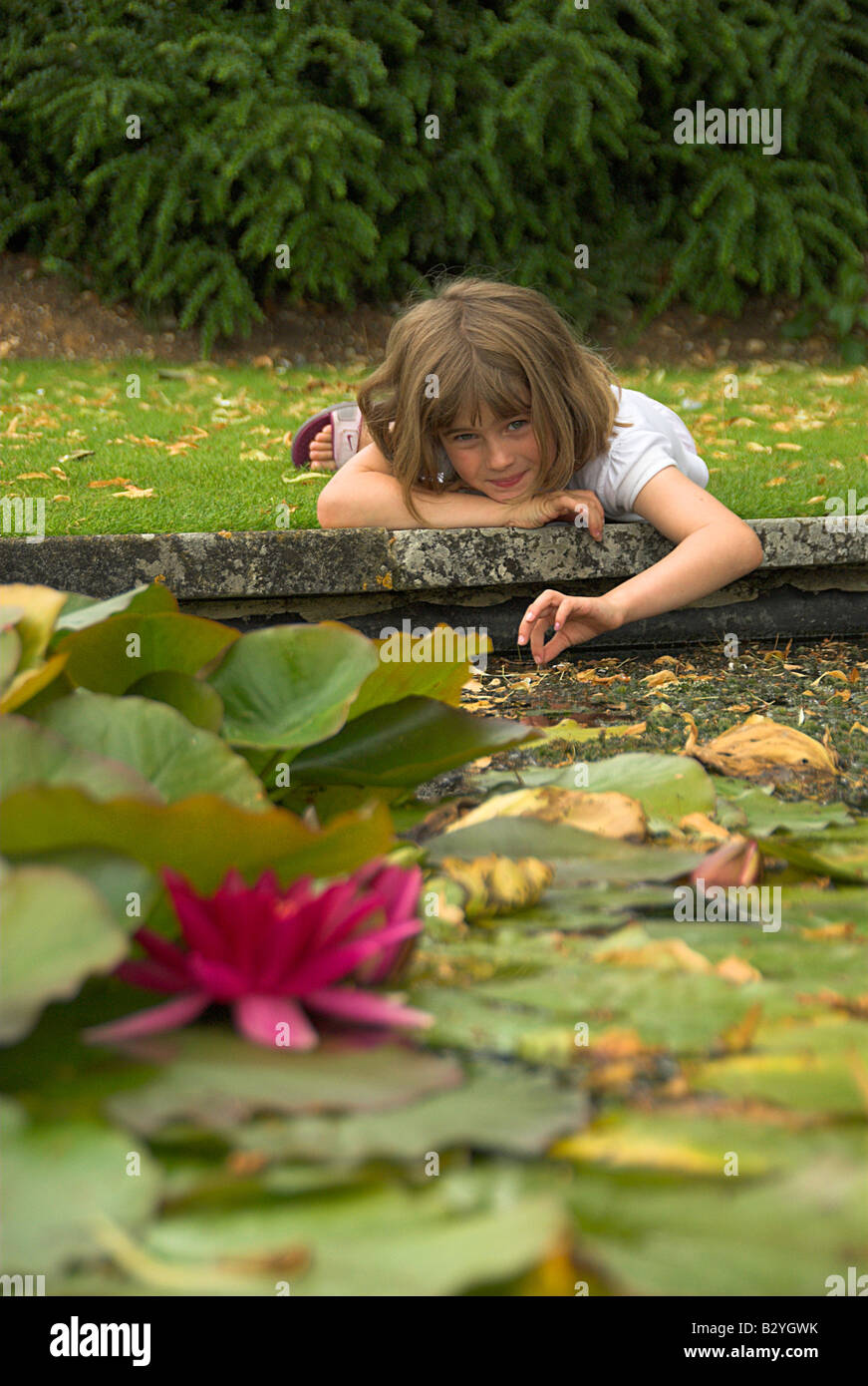 Little Girl Lying By A Garden Pond Stock Photo - Alamy