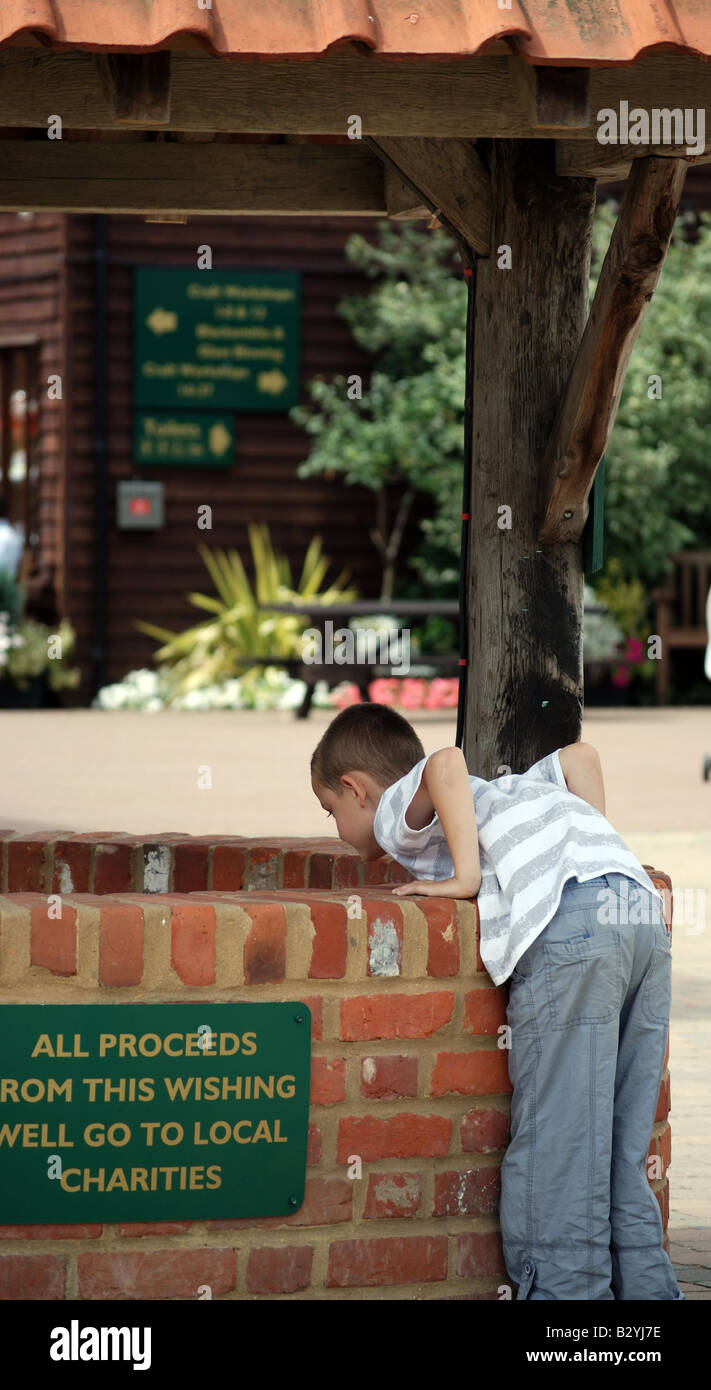 Boy looking into wishing well Stock Photo - Alamy