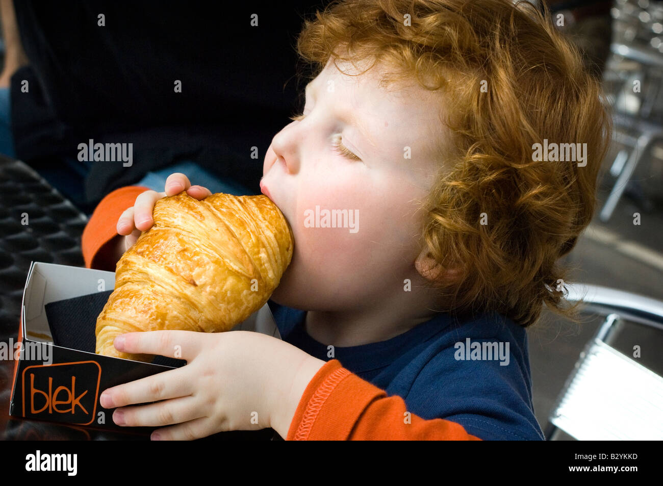 Young boy eating a croissant Stock Photo - Alamy