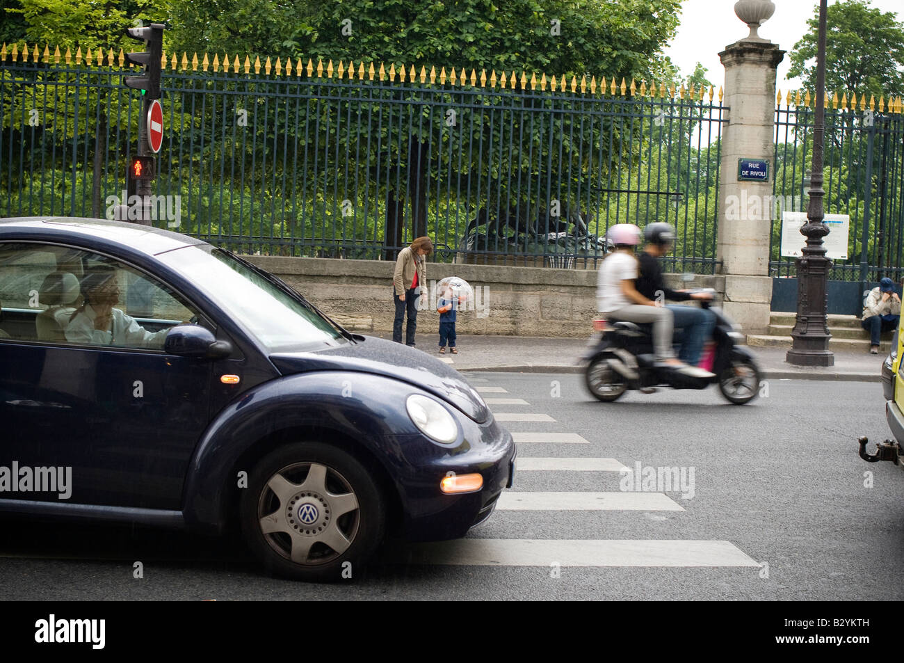 Mother and child by a zebra crossing, waiting to cross a busy road ...
