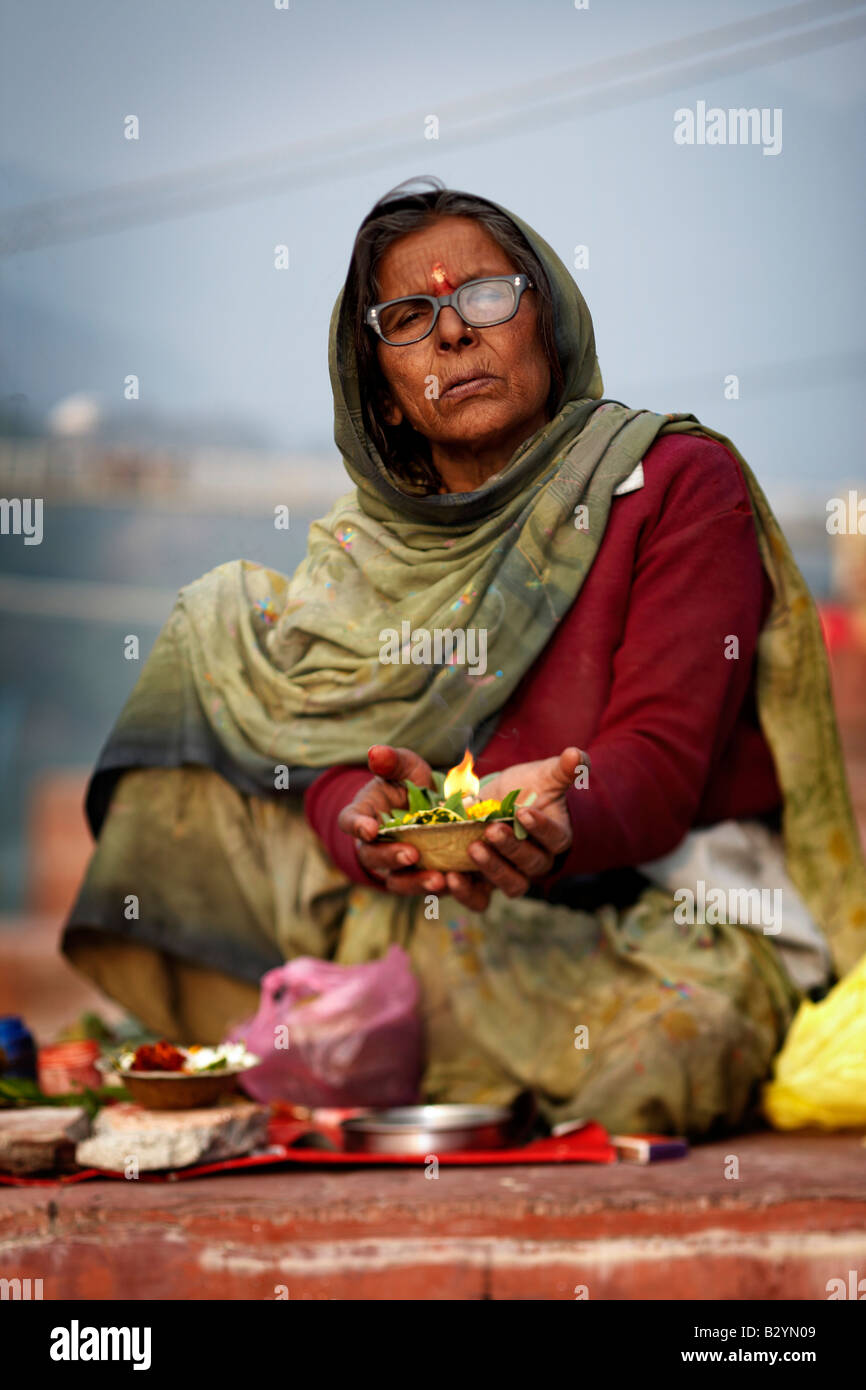 A old disheveled Indian woman sells a burning oil lamp to offer into ...