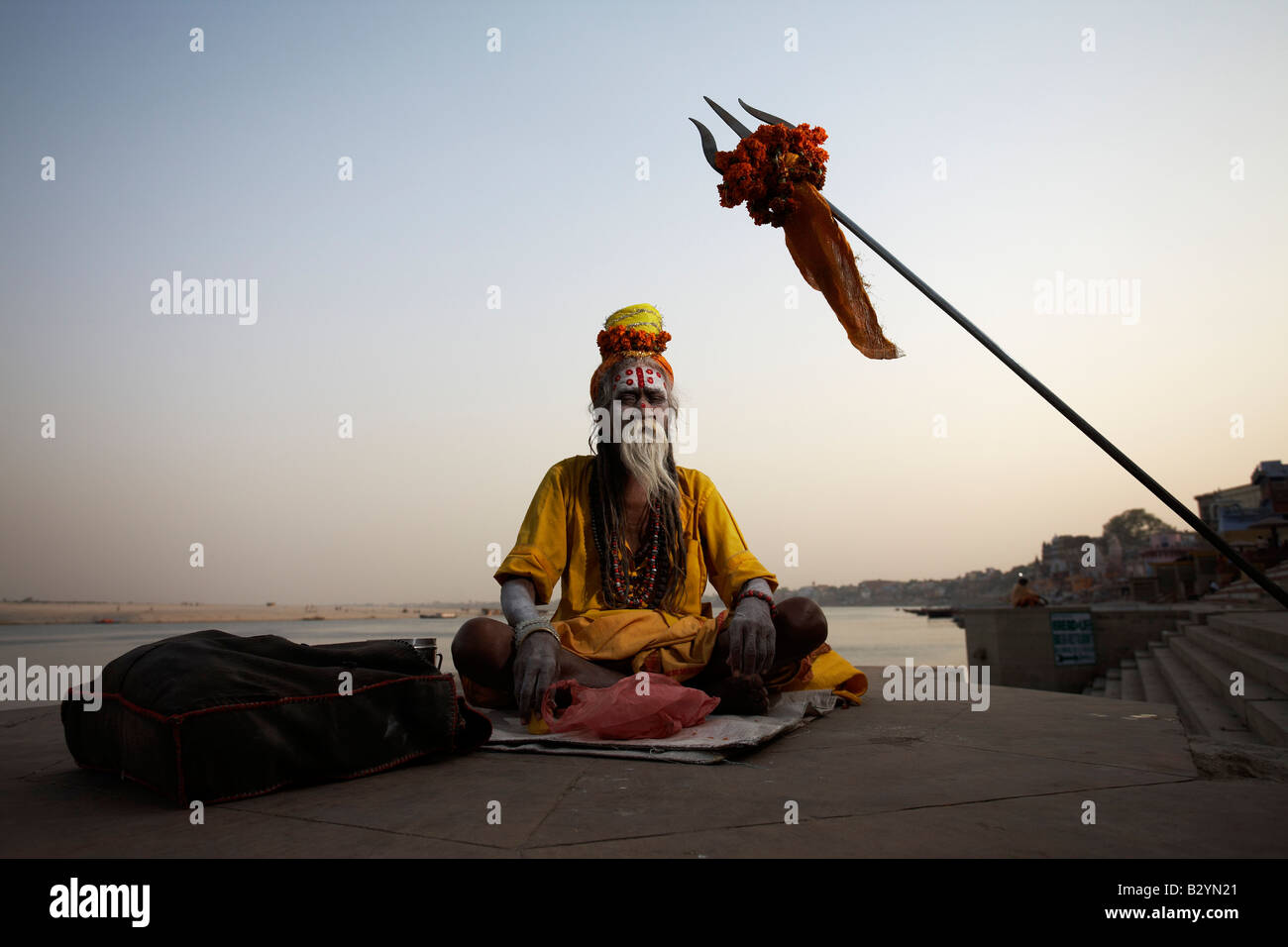 An Indian sadhu man sits in meditation posture near the bank of the ...