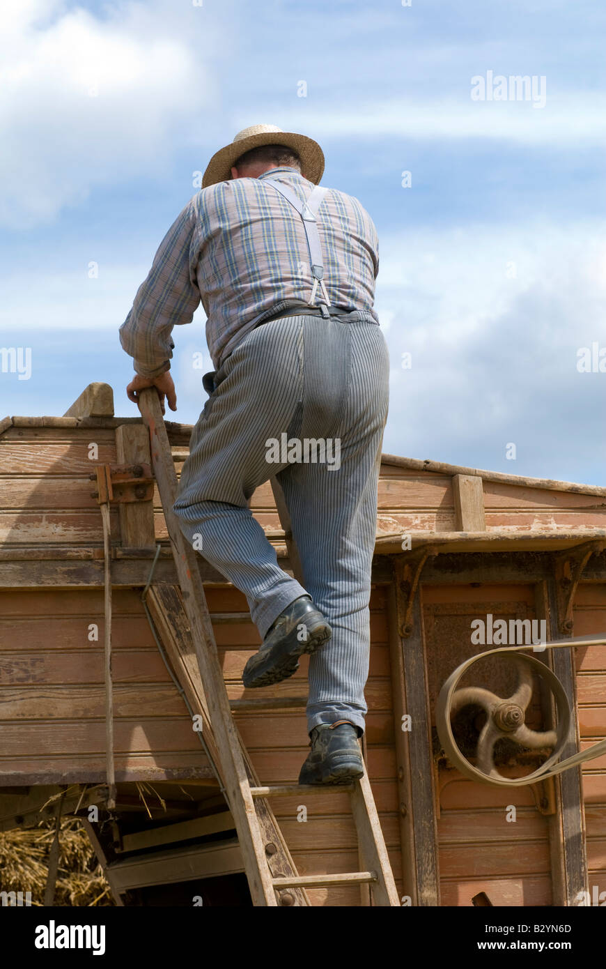 French farmer climbing onto old threshing machine at agricultural show ...