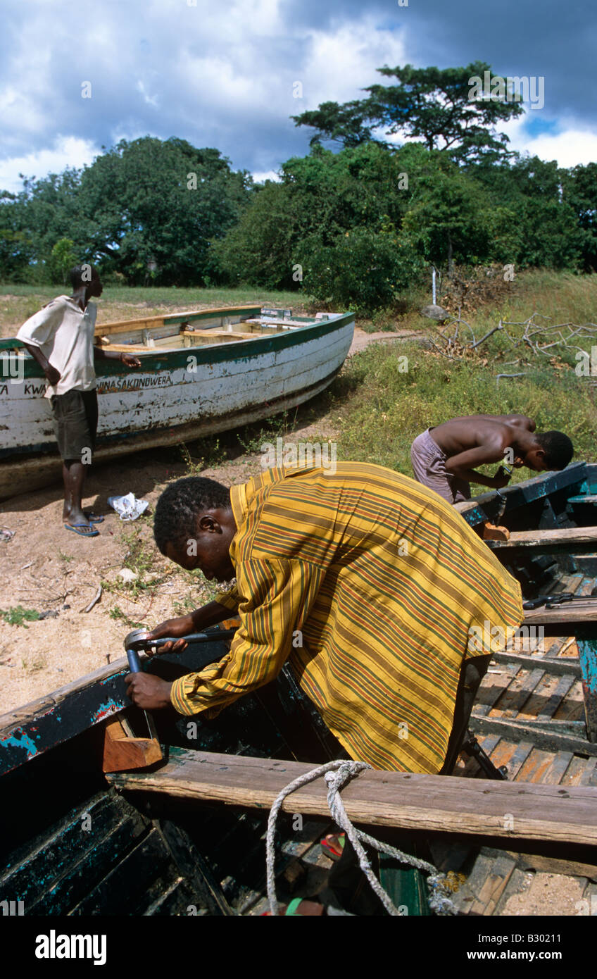 Carpenter repairing wooden boat on Lake Malawi beach, Malawi, Africa ...