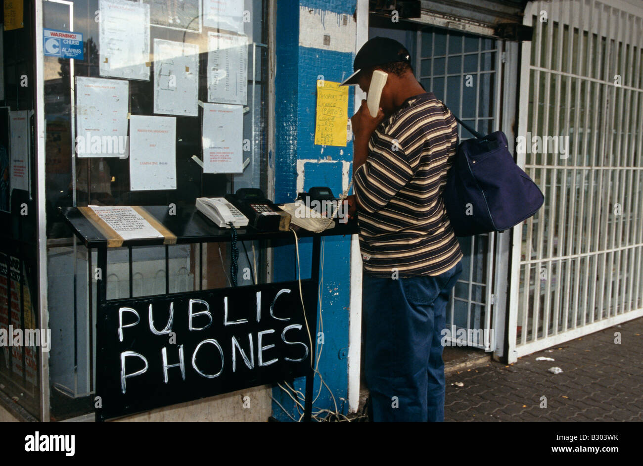 Man using public phone outside shop. Johannesburg, South Africa Stock ...