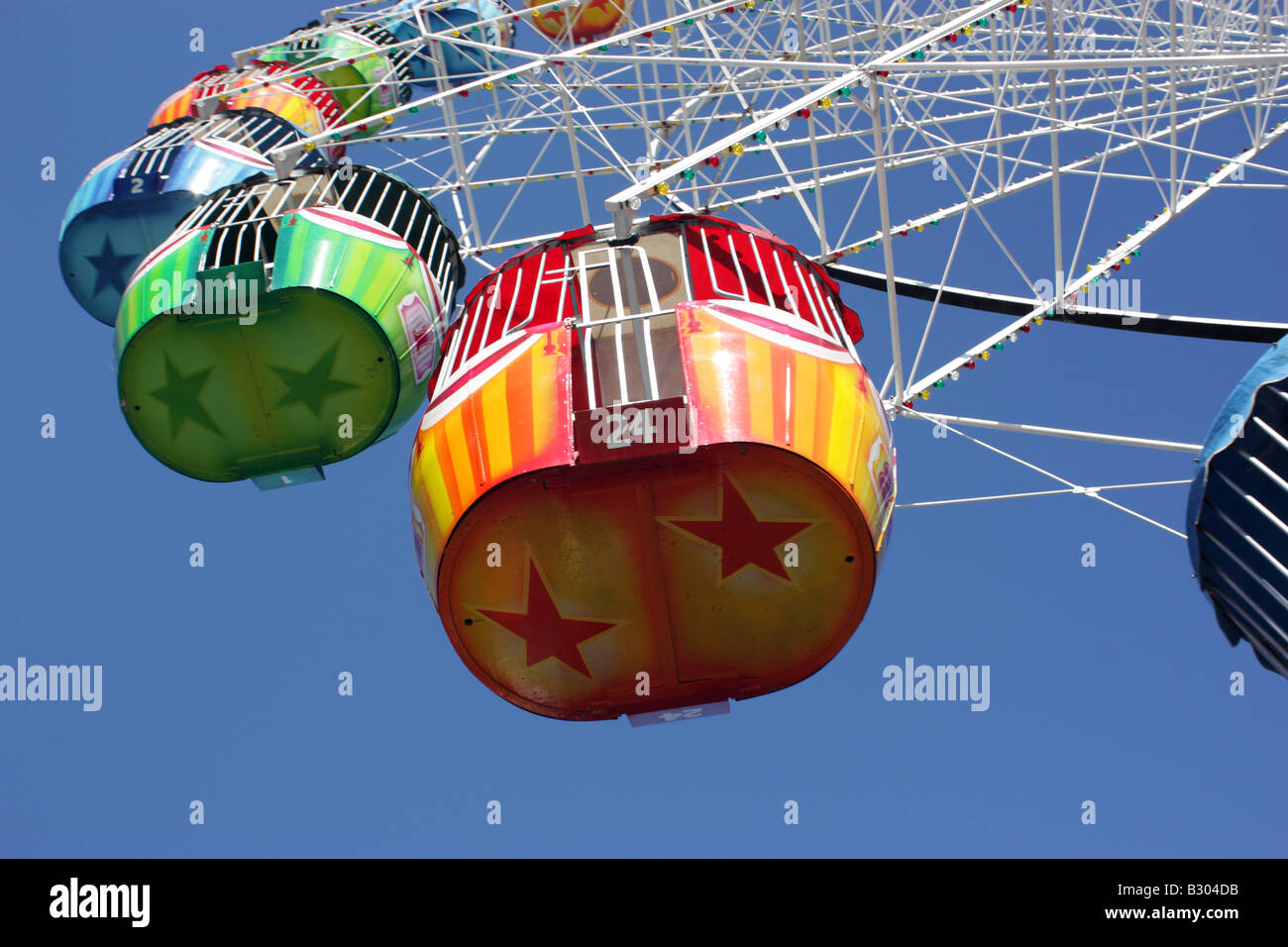 CLOSE UP OF FERRIS WHEEL CARRIAGES AT FAIRGROUND AGAINST BRIGHT BLUE ...