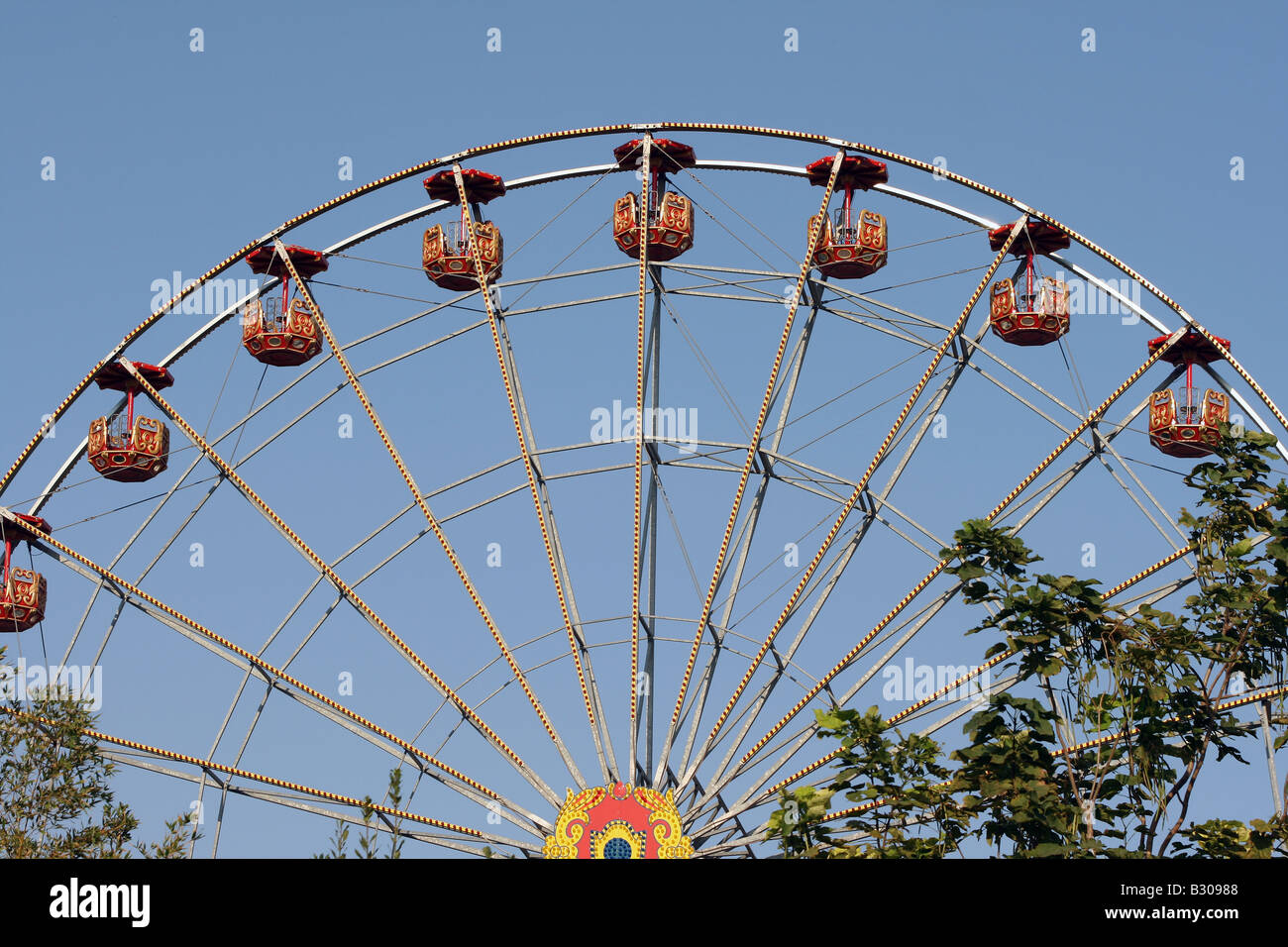 big spinning wheel behind a tree at amusement park and blue sky ...