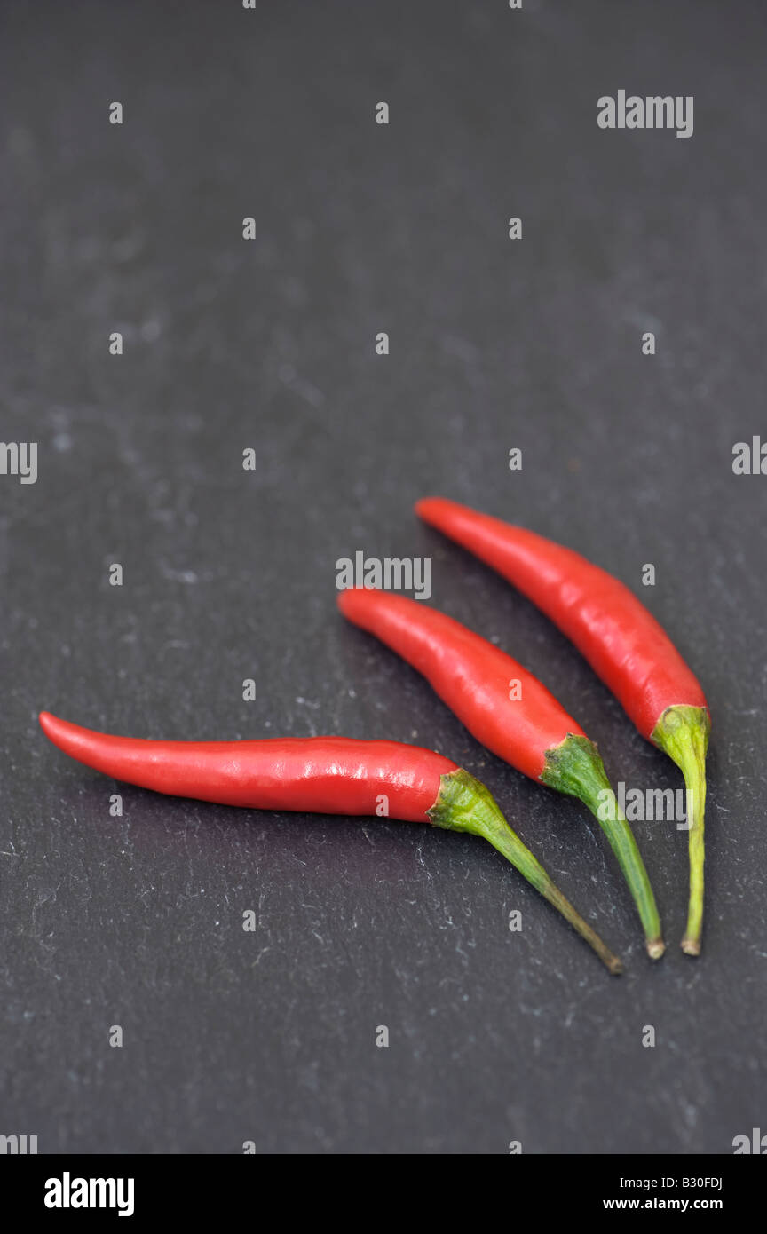 Three red chilis on slate Stock Photo - Alamy