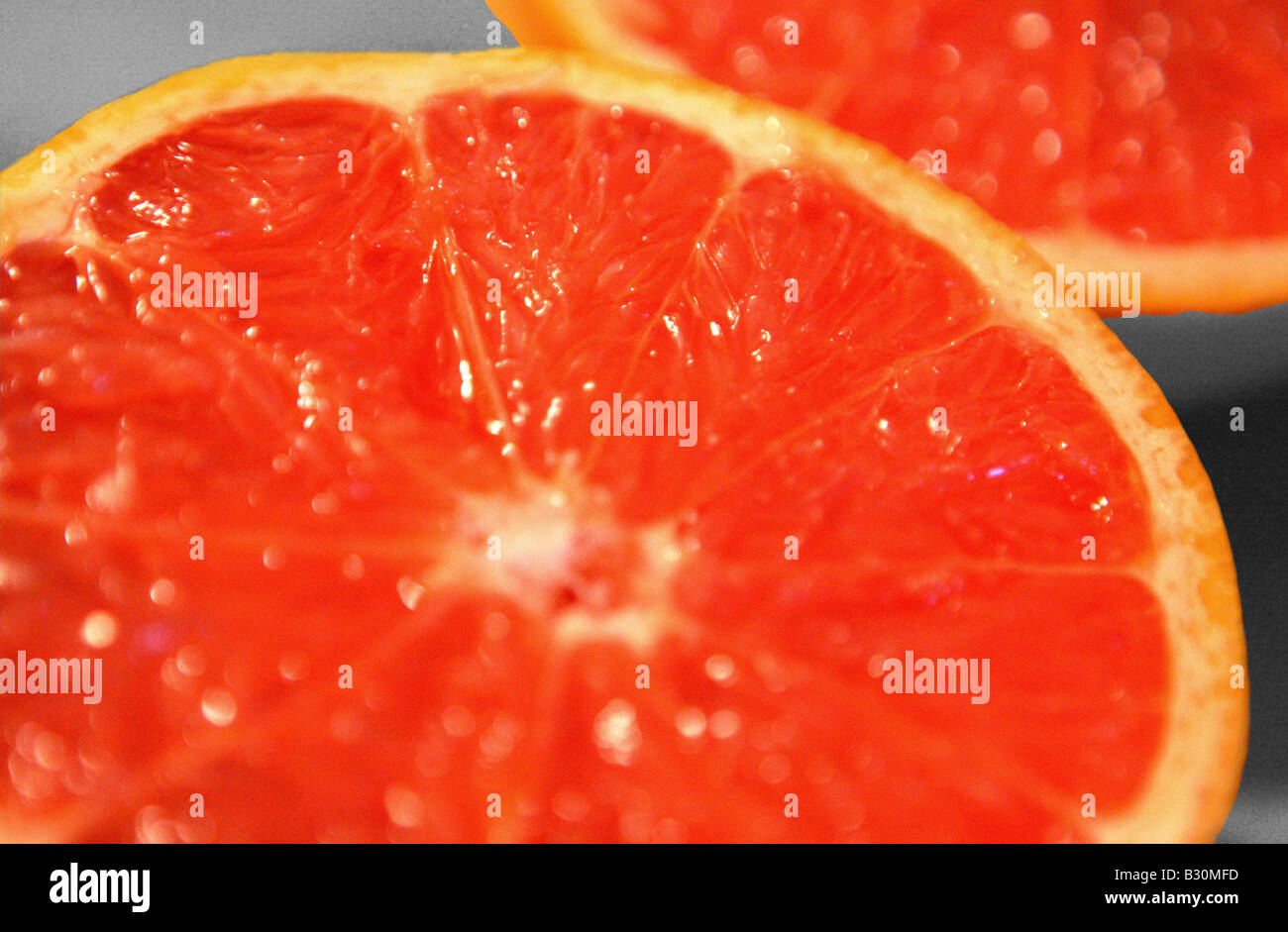 A brightly-colored juicy pink sliced grapefruit with a black and white ...