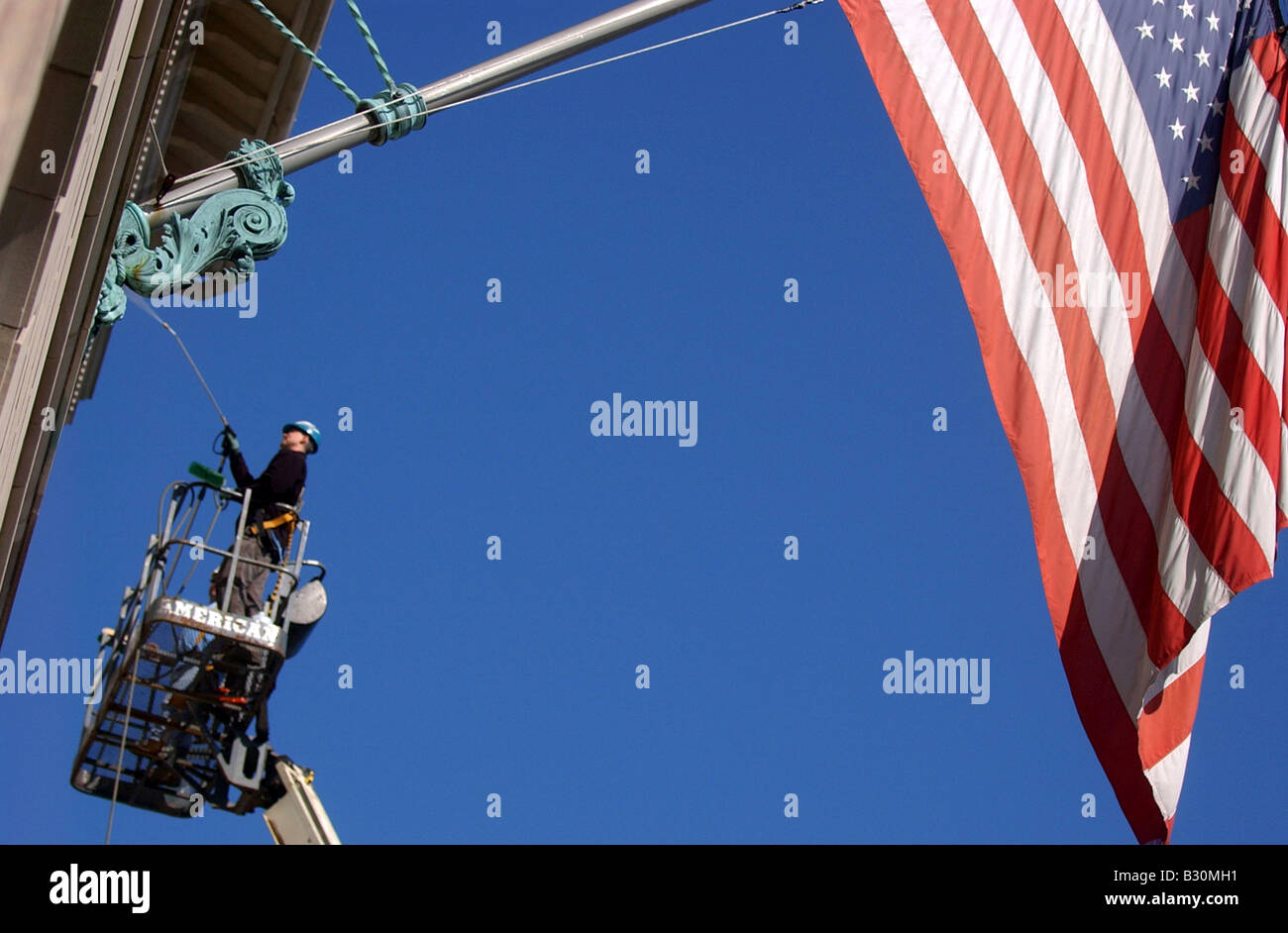 A man washes windows high up on a building as a giant American flag ...