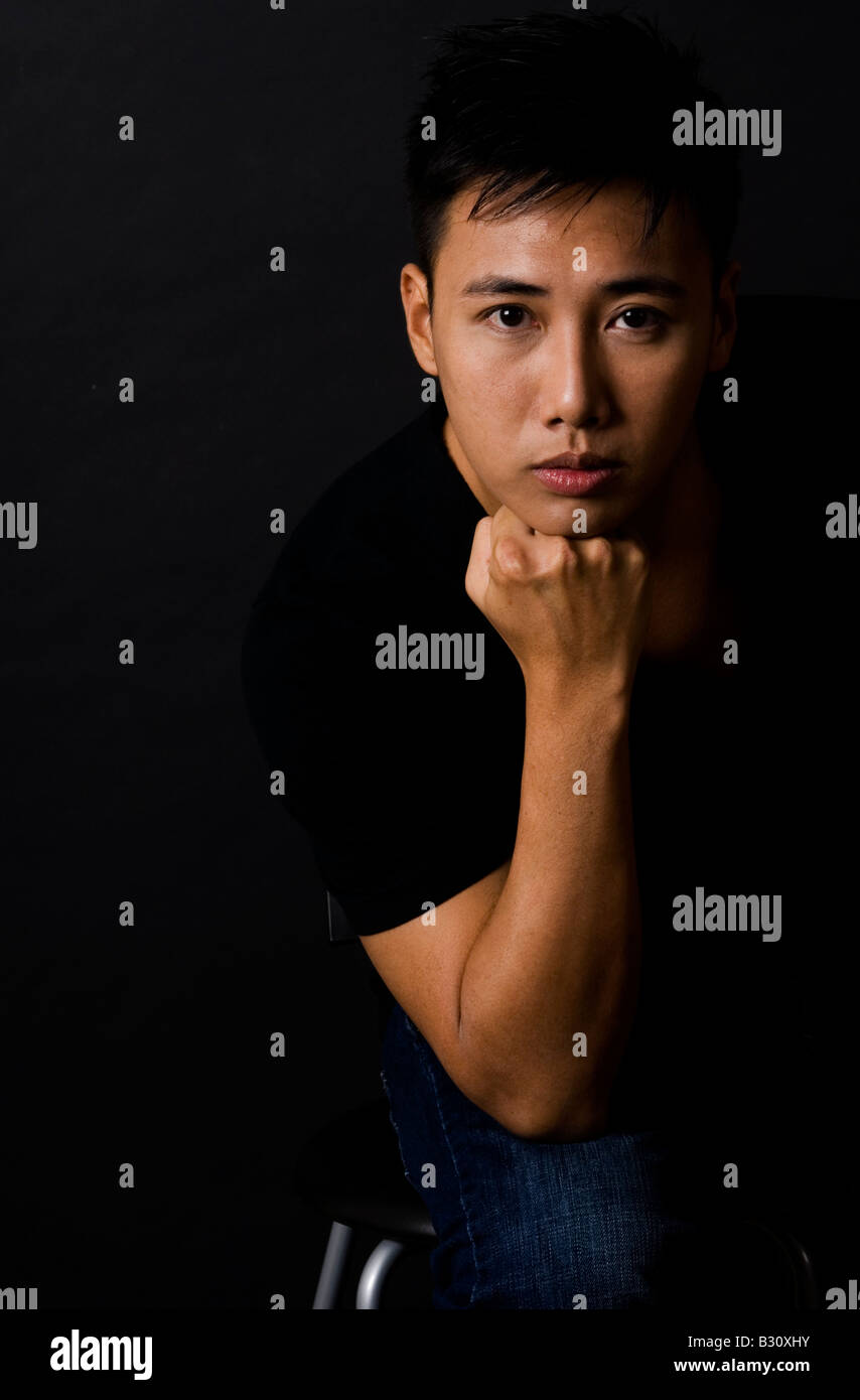 A chinese male model sits on a stool and stares moodily at the camera ...