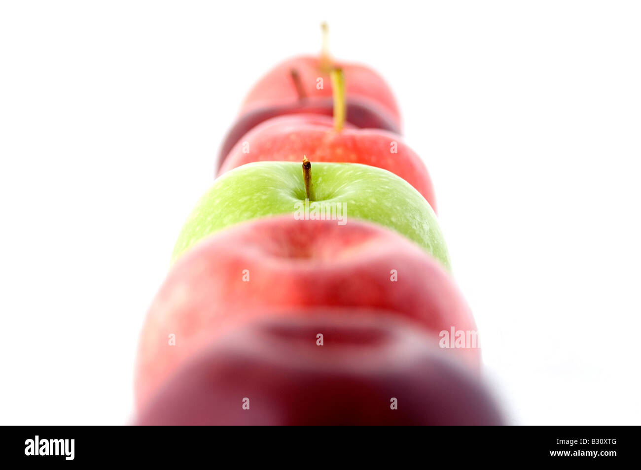 A green apple in a line of red Stock Photo - Alamy