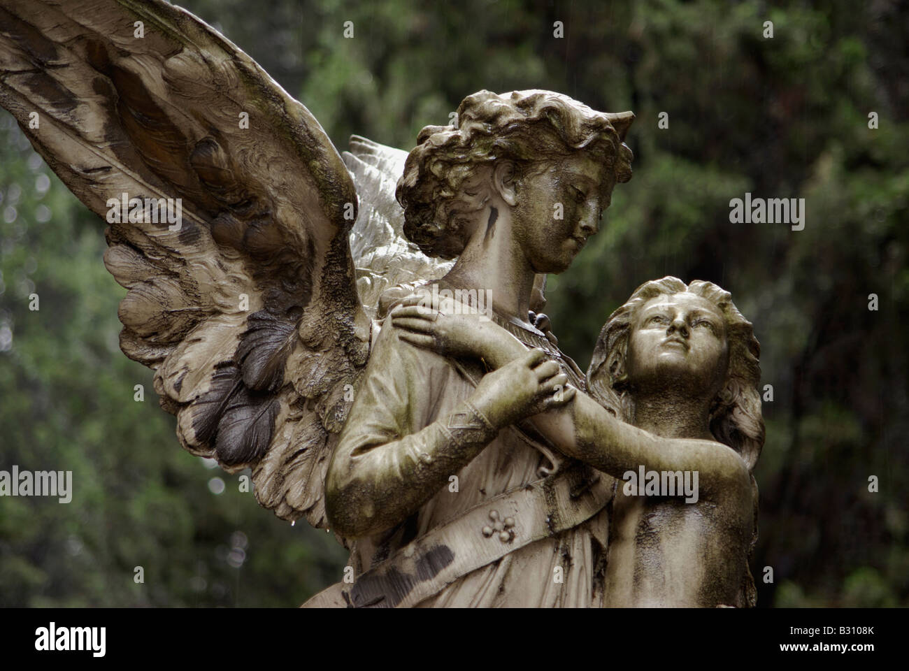 statue sculpture of an angel supporting a young child representing a ...
