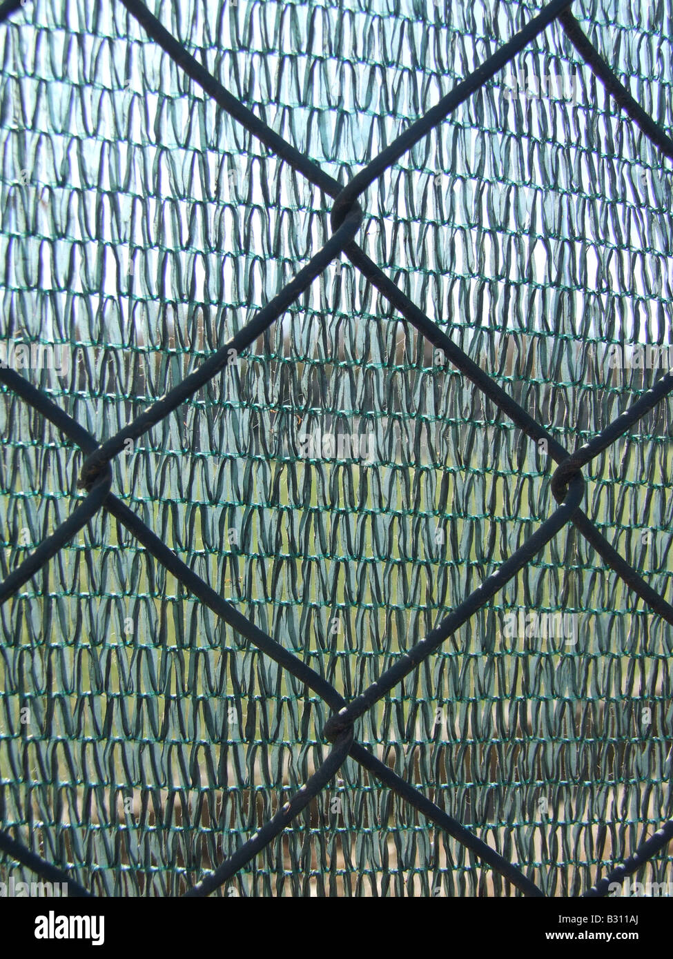 high fence with green mesh cover and sky Stock Photo - Alamy