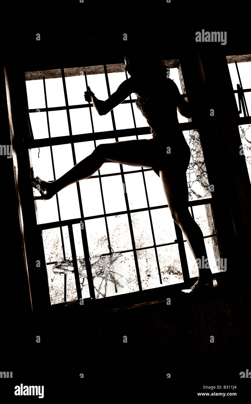 young woman climbing on window Stock Photo - Alamy