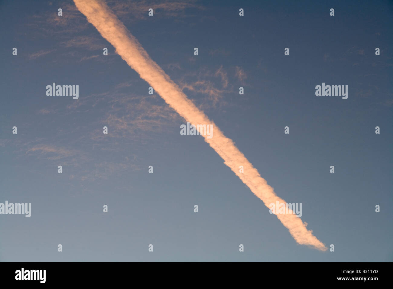 Pink jet contrails against a blue sky at sunset Stock Photo - Alamy