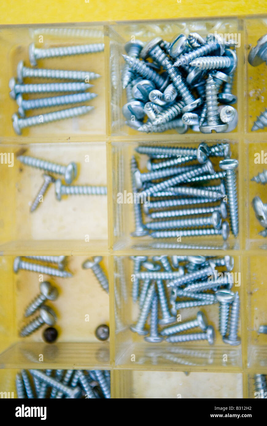 screws in transparent container against yellow background Stock Photo ...