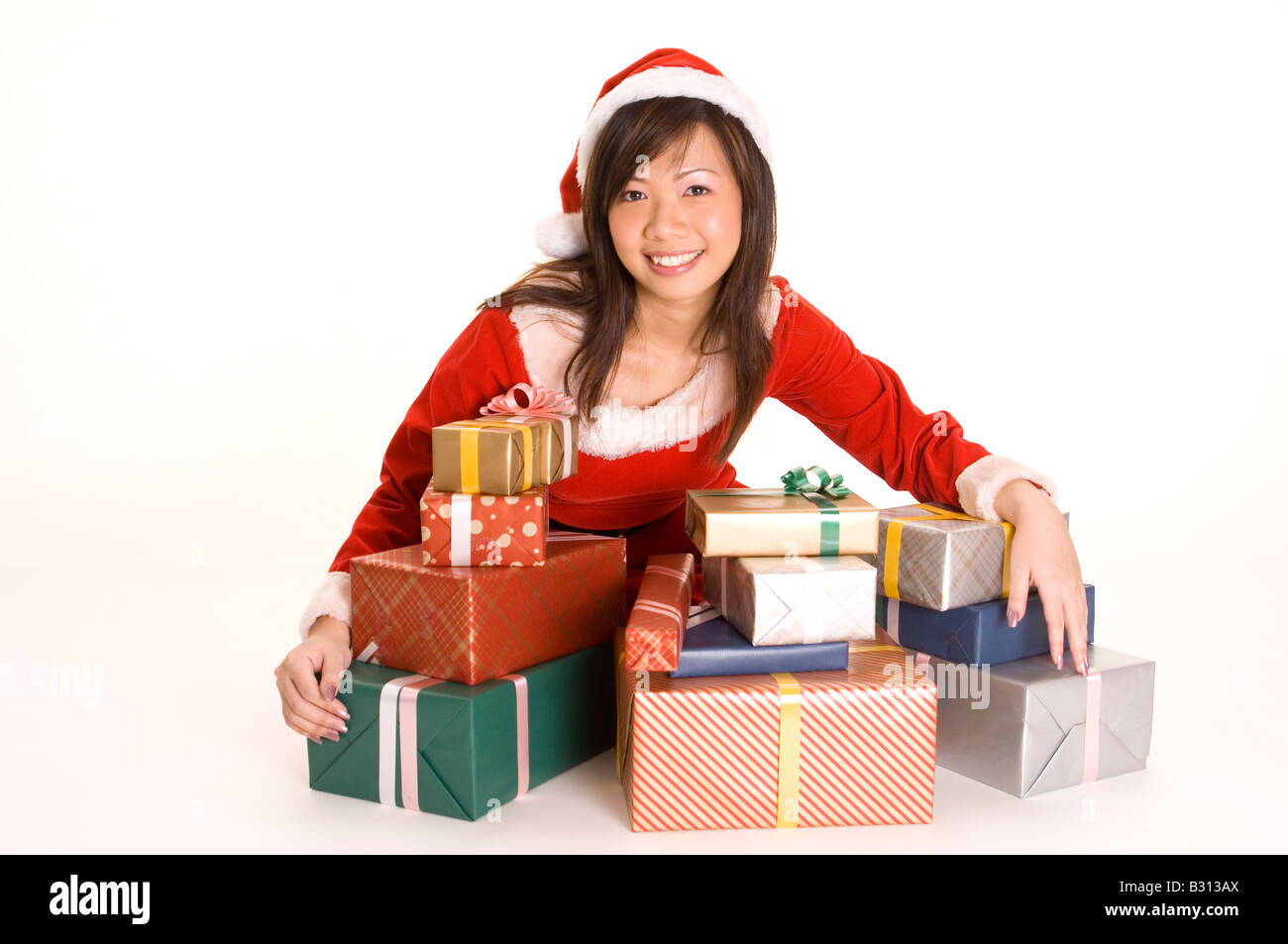 A cute asian woman dressed as santa sits with a load of presents Stock ...