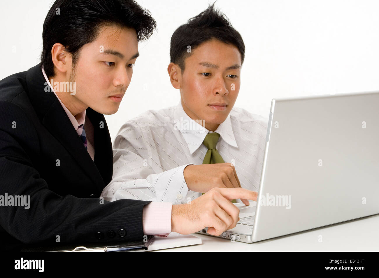 Two young businessmen working on a laptop computer Stock Photo - Alamy