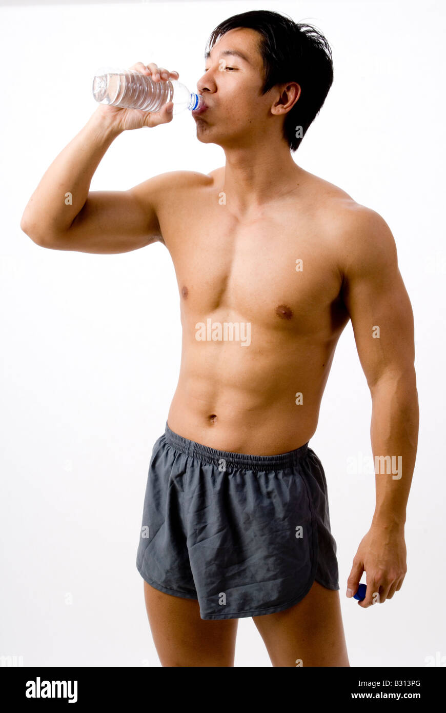 A muscular asian man drinks from a clear bottle of water Stock Photo ...