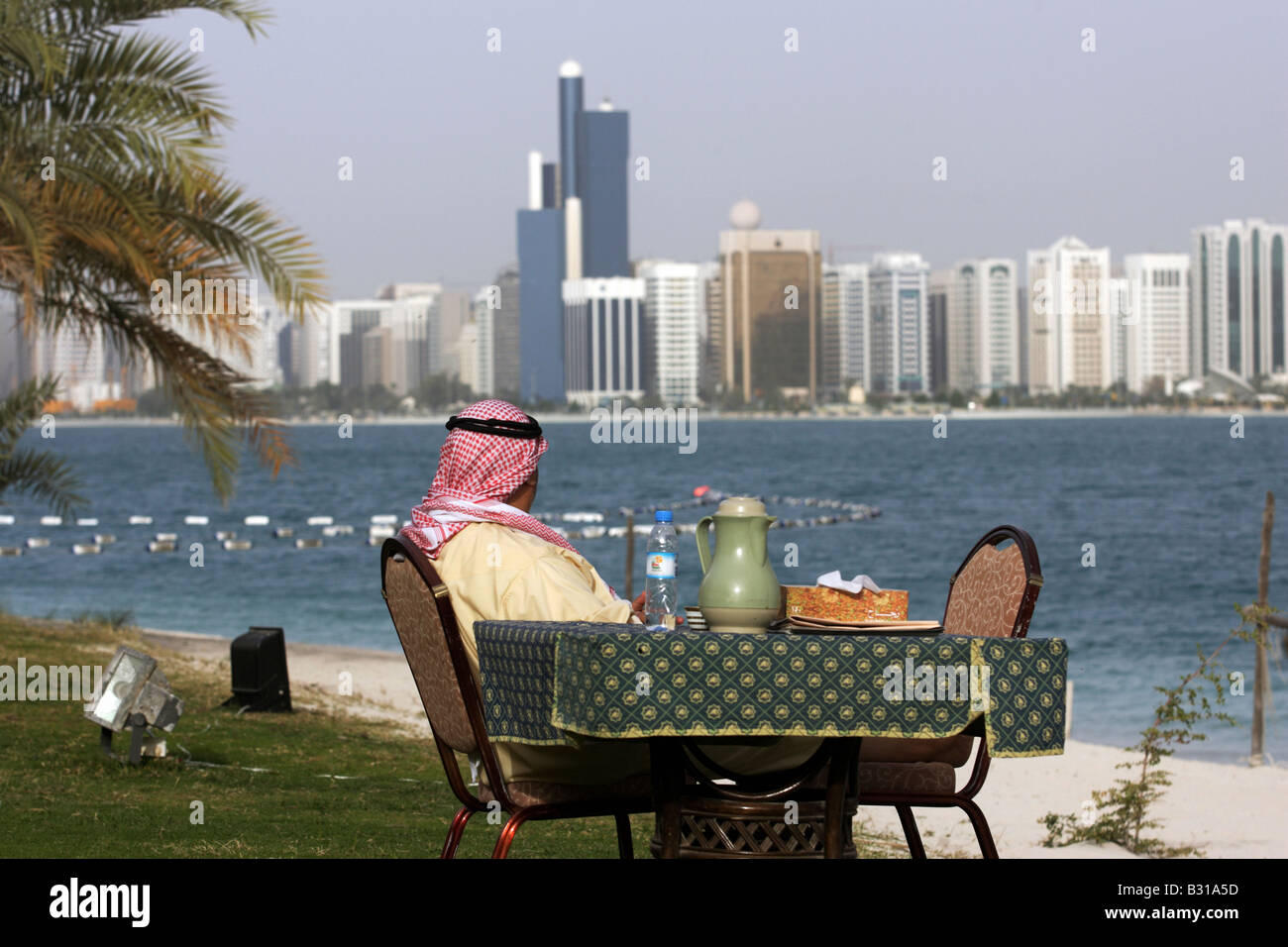 Arab man sitting at a table and enjoying the cityscape of Abu Dhabi ...