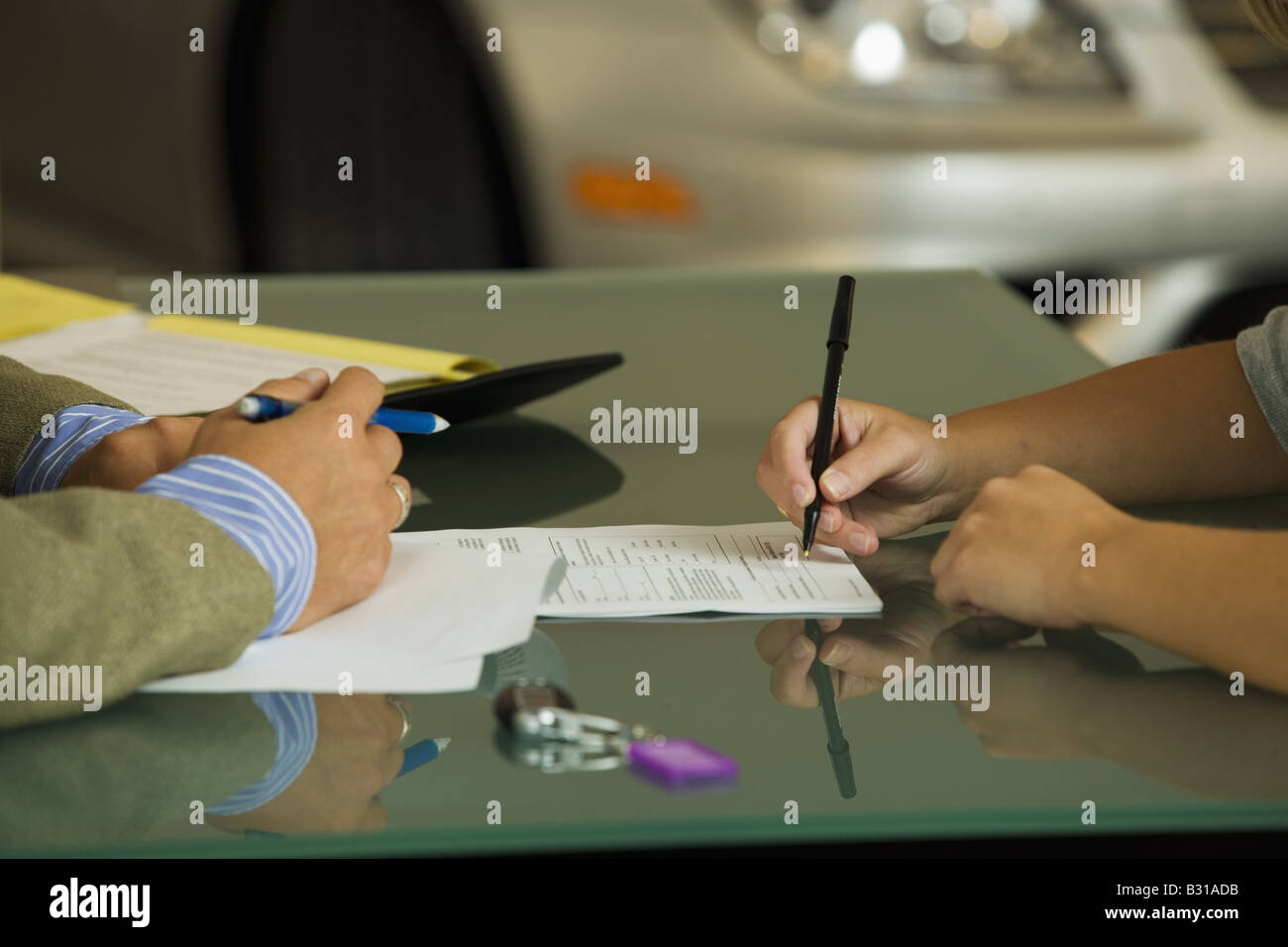 Woman signing paperwork with car salesman Stock Photo - Alamy