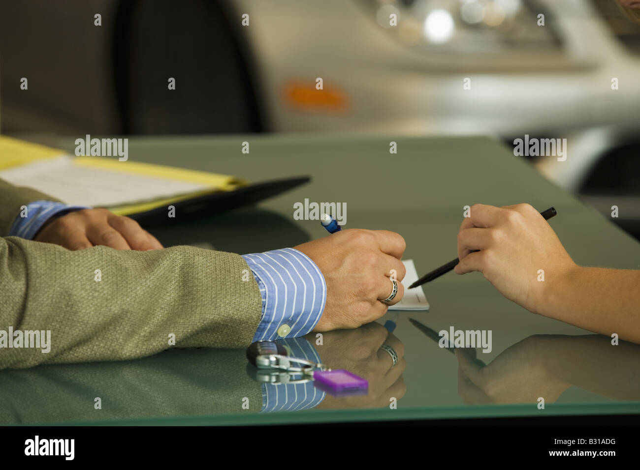 Woman signing paperwork with car salesman Stock Photo - Alamy
