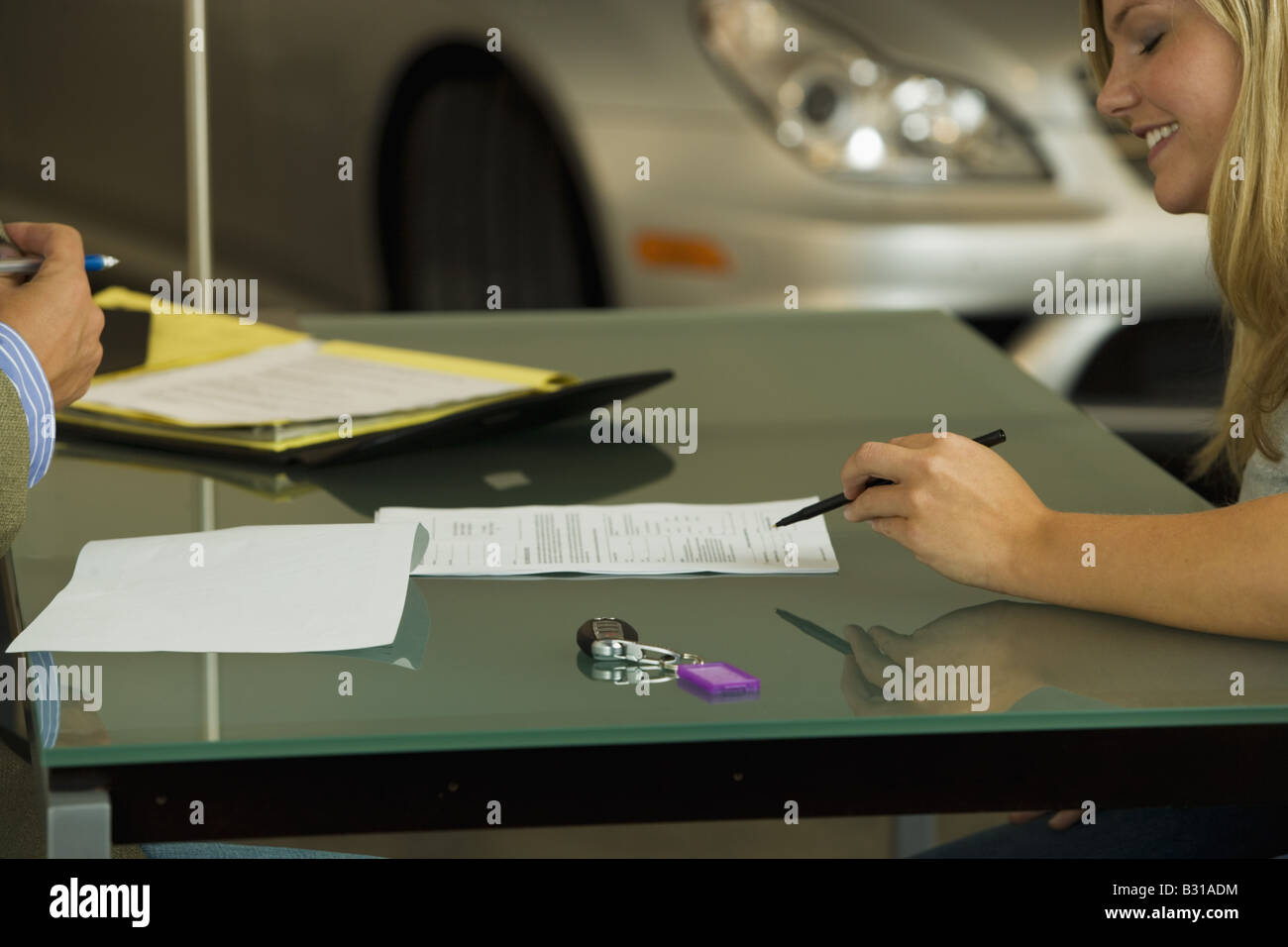 Woman signing paperwork with car salesman Stock Photo - Alamy