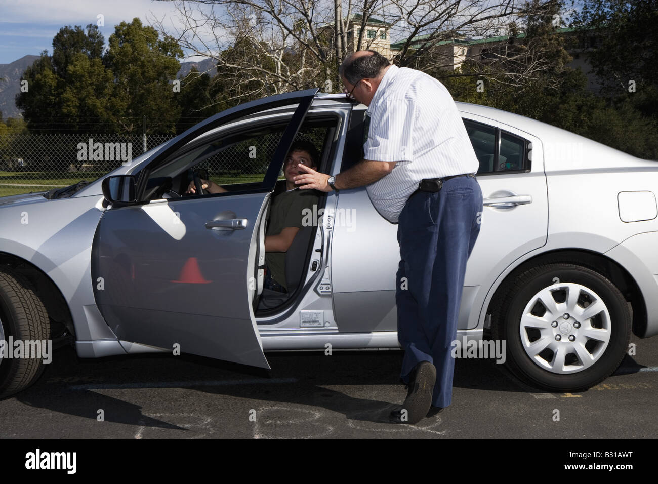 Driving instructor talking with teen driver Stock Photo - Alamy