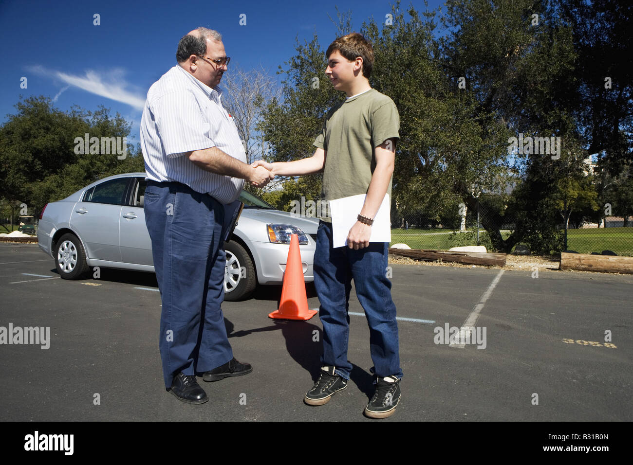 Teen driver shaking hands with driving instructor Stock Photo - Alamy
