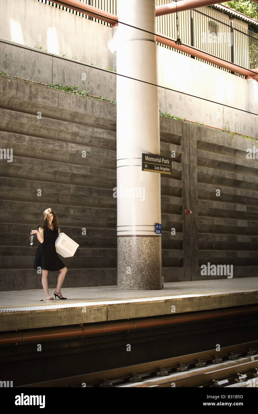 Young woman on train platform with box and broken shoe Stock Photo - Alamy