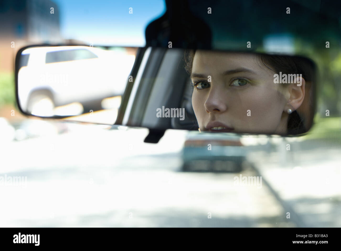 Young woman looking in rear view mirror Stock Photo - Alamy