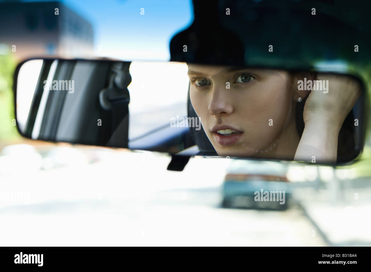 Young woman looking in rear view mirror Stock Photo - Alamy