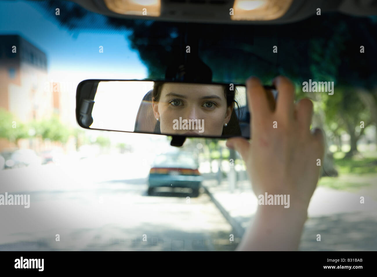 Young woman looking in rear view mirror Stock Photo - Alamy