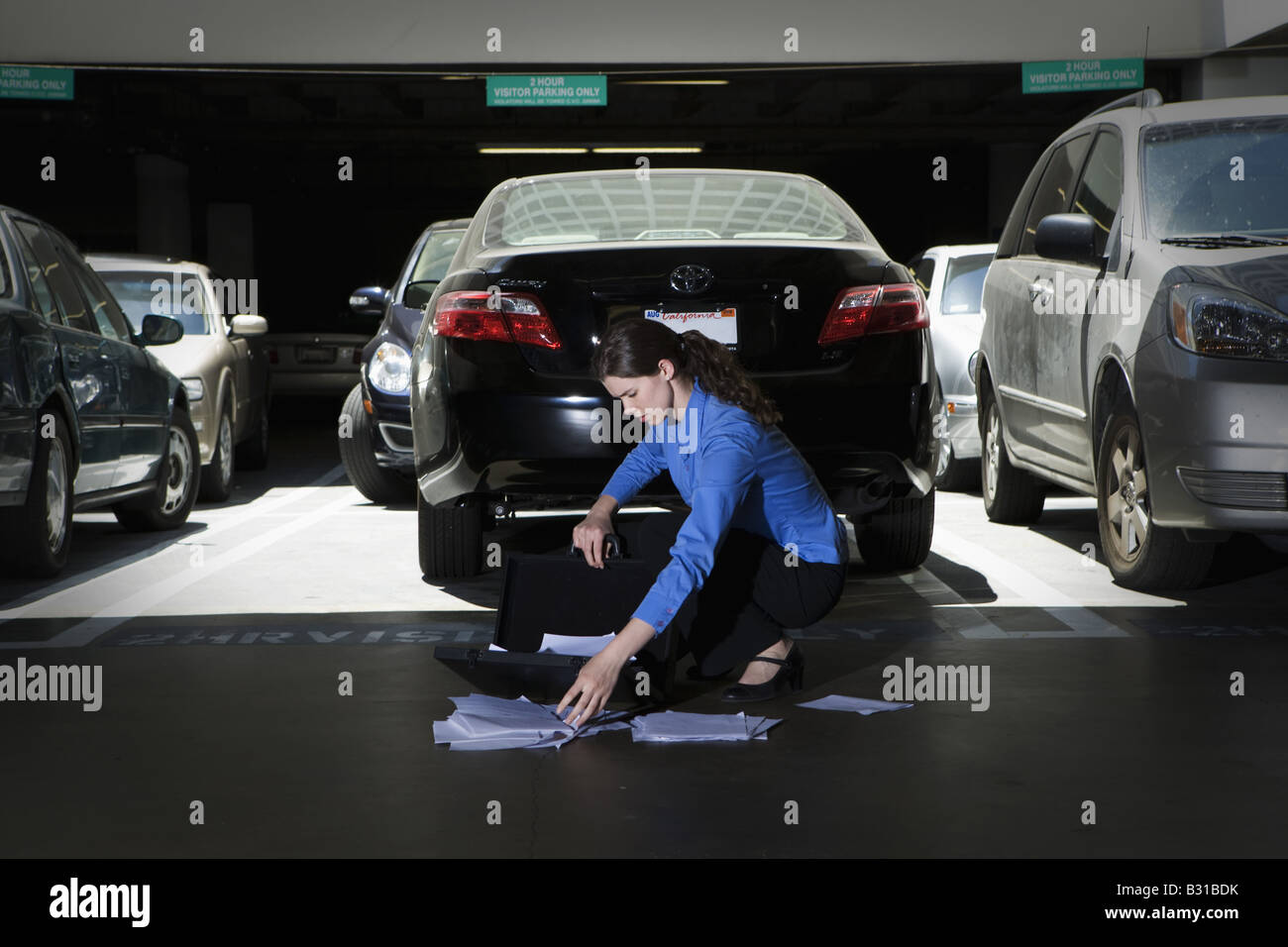 Young woman picking dropped papers from floor in elevator lobby Stock ...