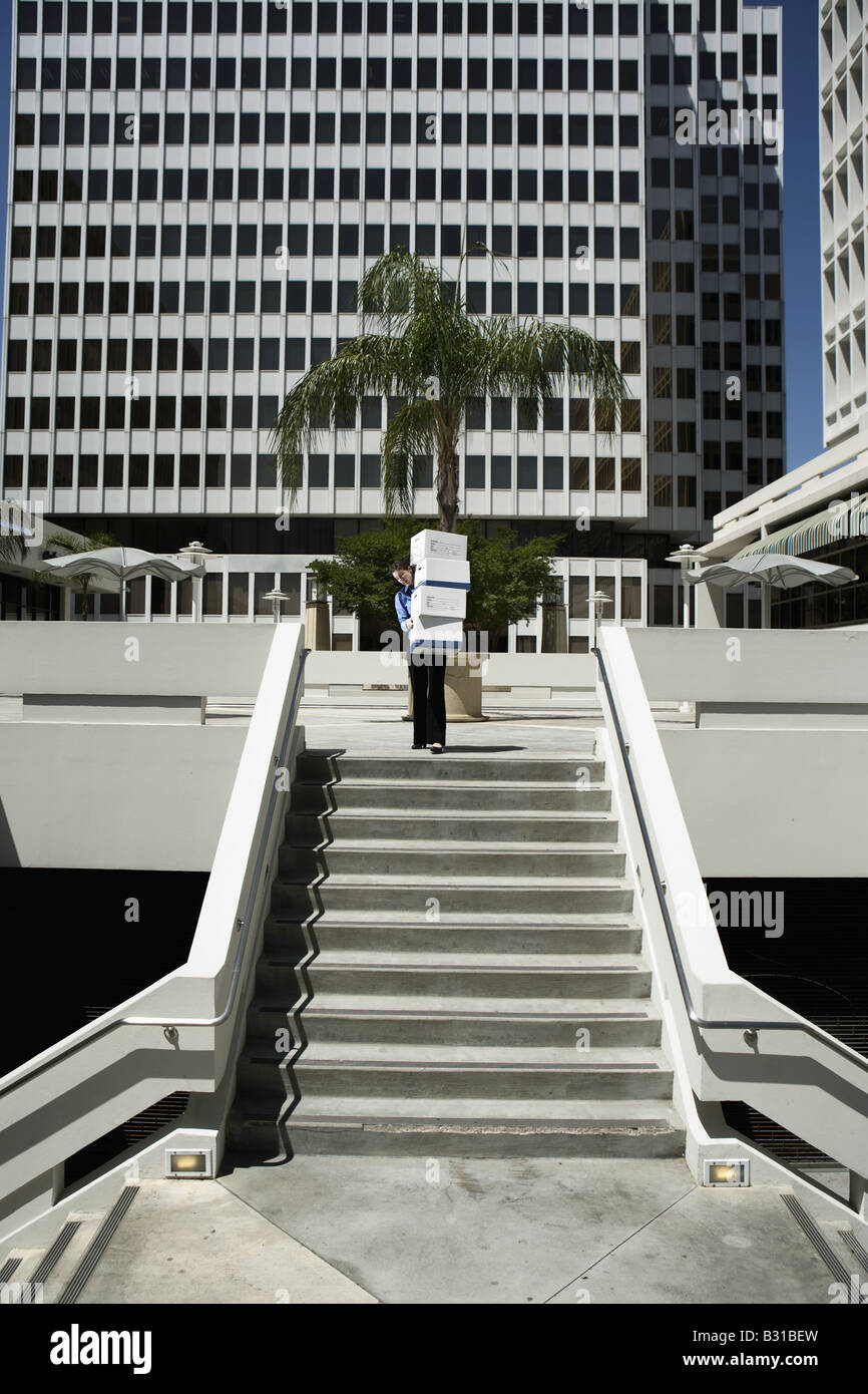 Girl Friday carrying stack of boxes down steps Stock Photo - Alamy
