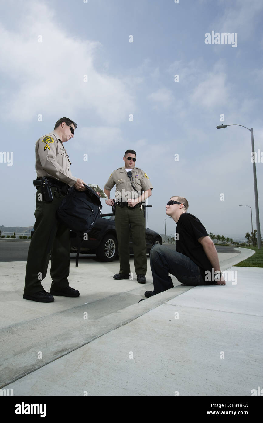 Two police officers discovering drugs in backpack of arrested man Stock ...